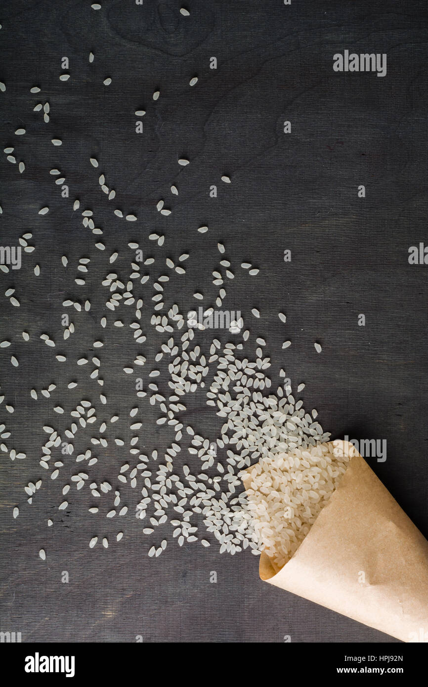 White rice scattered over the dark wooden table of a paper bag. View ...