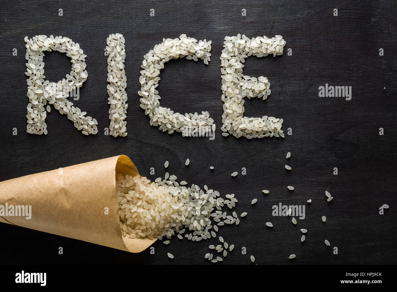 White rice scattered over the dark wooden table of a paper bag. View ...