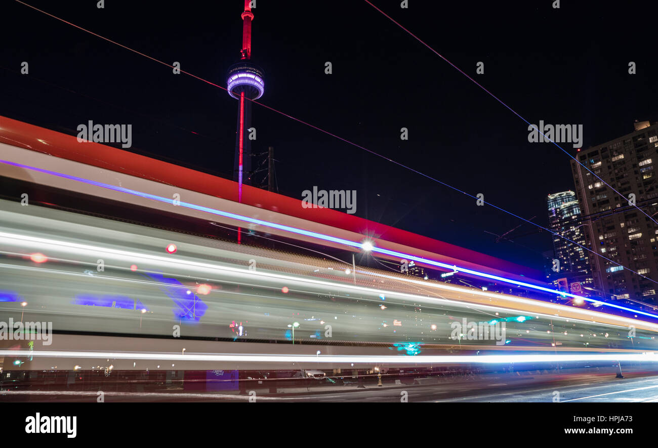 Toronto CN Tower by Night with a street car passing by creating light ...