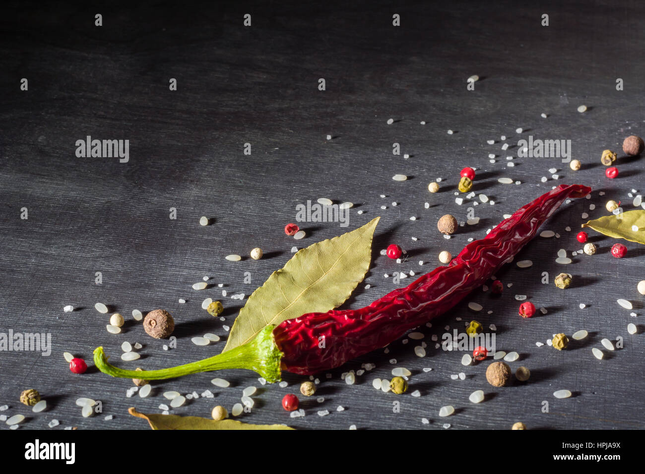 Red pepper pungent spices and bay leaf on the black tree. View from ...