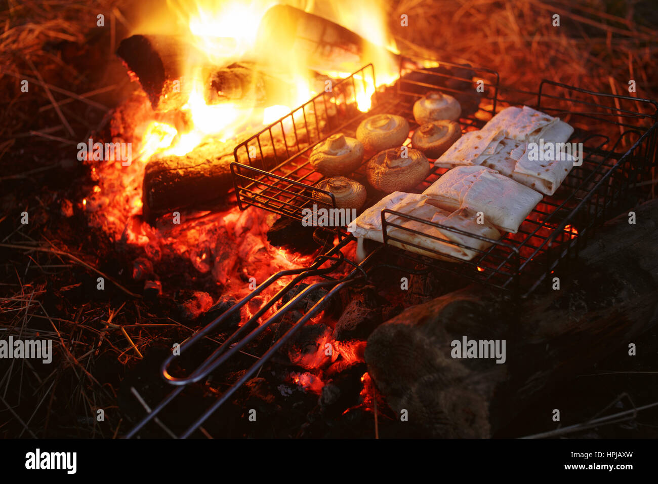 Cooking healthy food on fire in wilderness. Cheese and mushrooms ...
