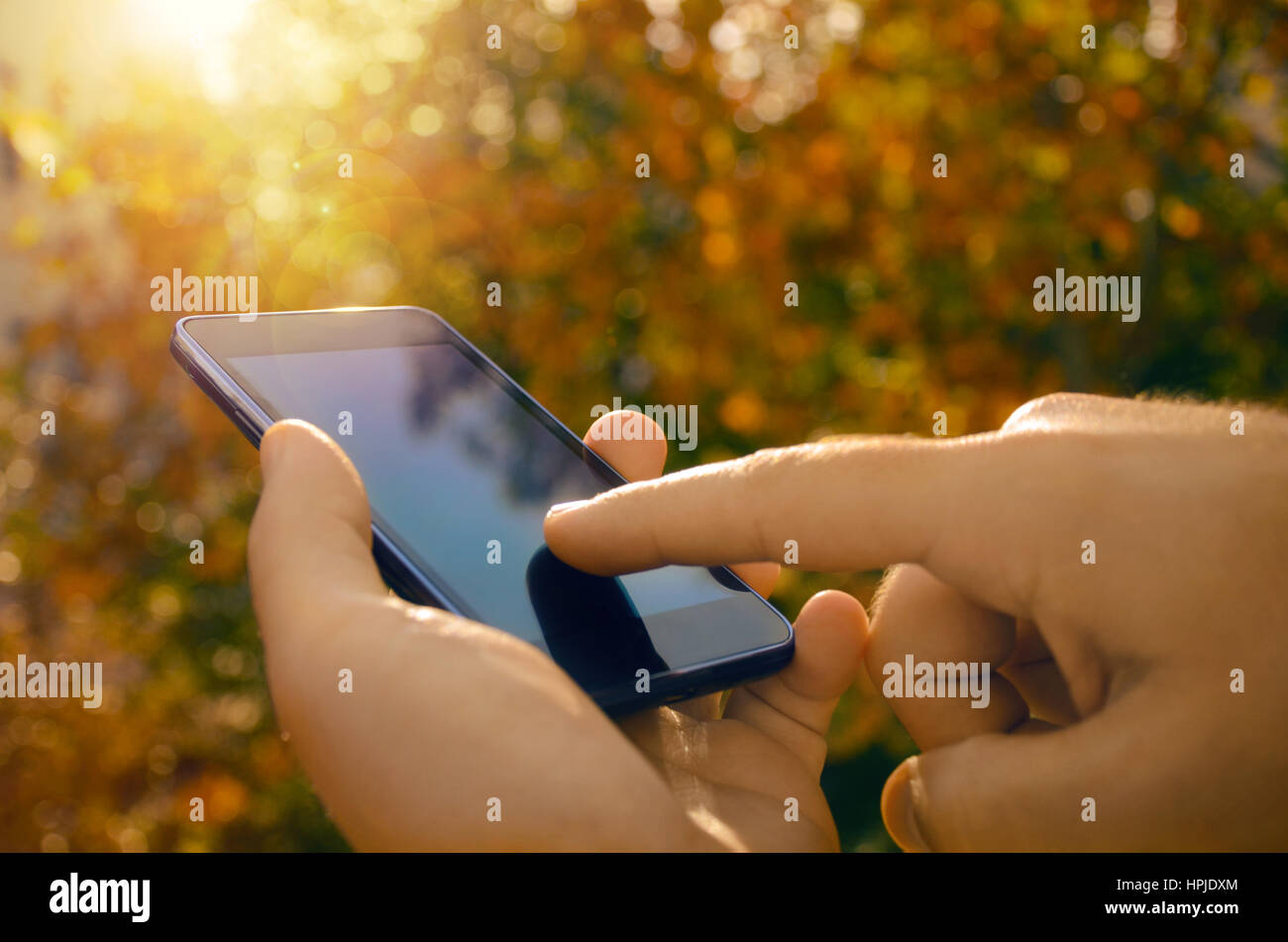 Man using a smart phone, nature background. Image can be used for ...