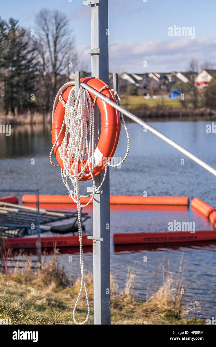 An orange life saver ring with a rescue rope and pole at the waters ...