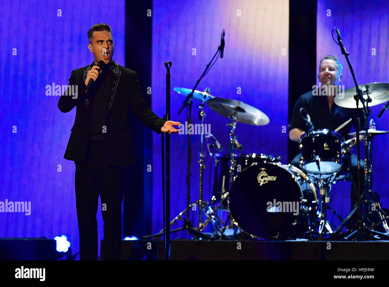 Robbie Williams gestures because of a broken microphone as he performs ...