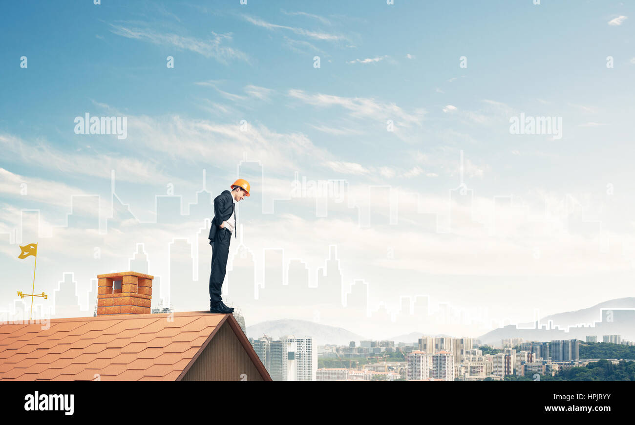 Engineer man standing on roof and looking down. Mixed media Stock Photo ...