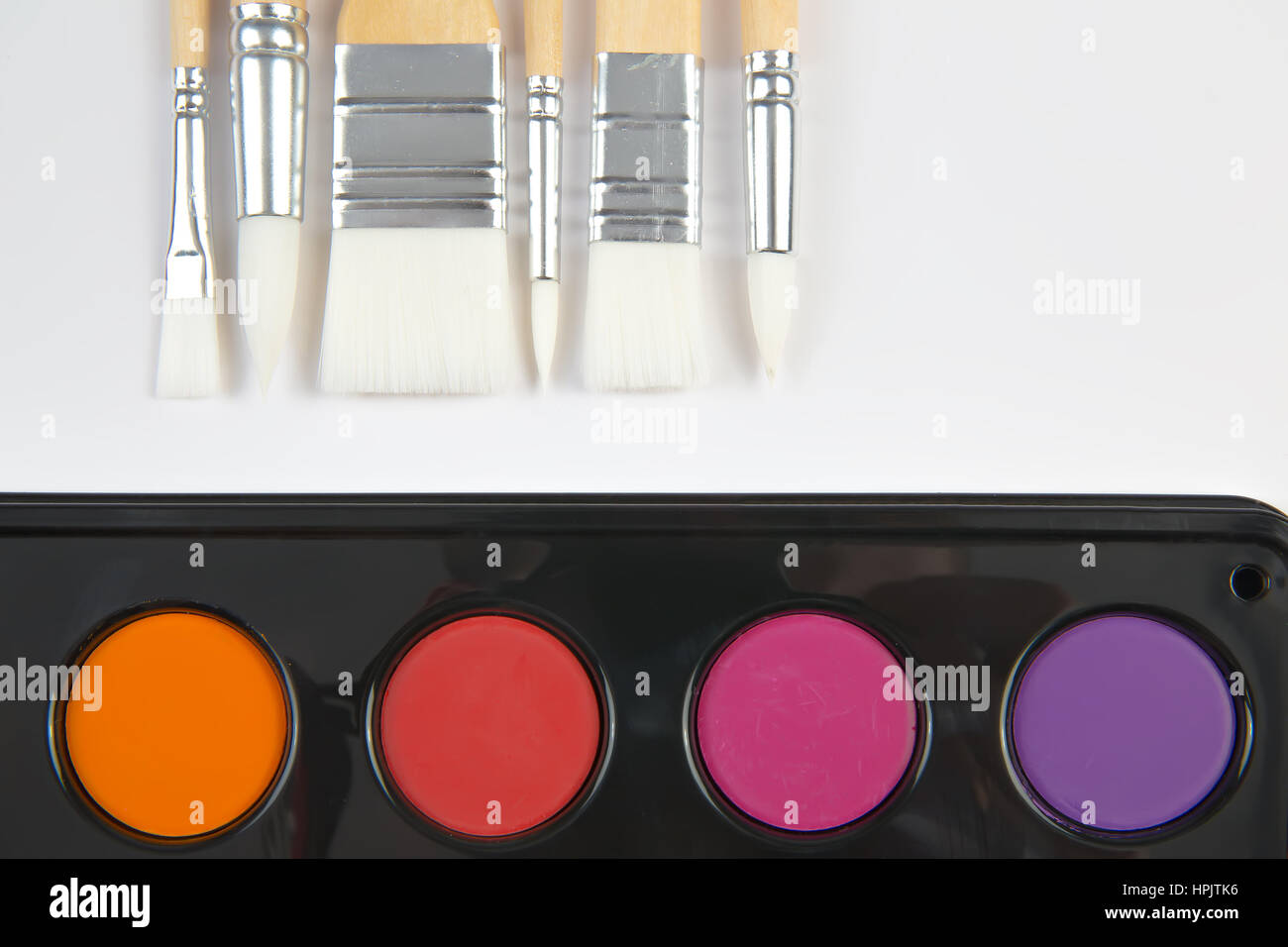 White paintbrushes with wooden handle and color paint on clear ...