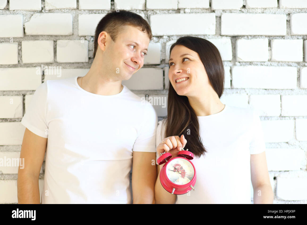 Young smiling couple with red alarm clock Stock Photo - Alamy