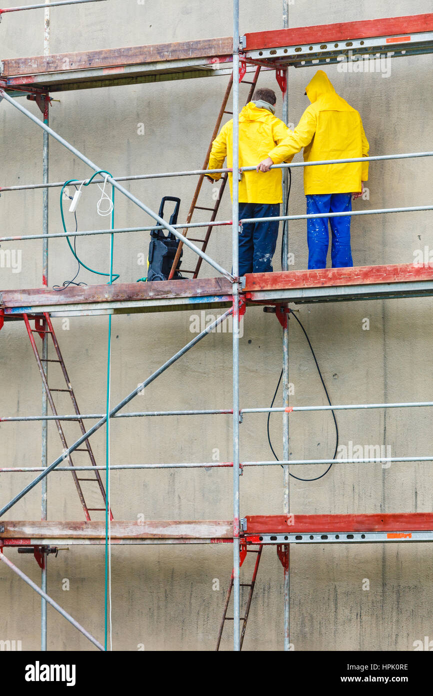 Men cleaning wall. Scaffolding, construction site in progress. Building ...