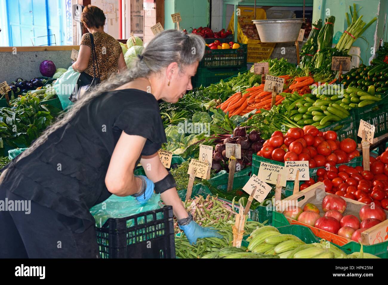 Cretan stallholder sorting vegetables on a market stall in the city ...
