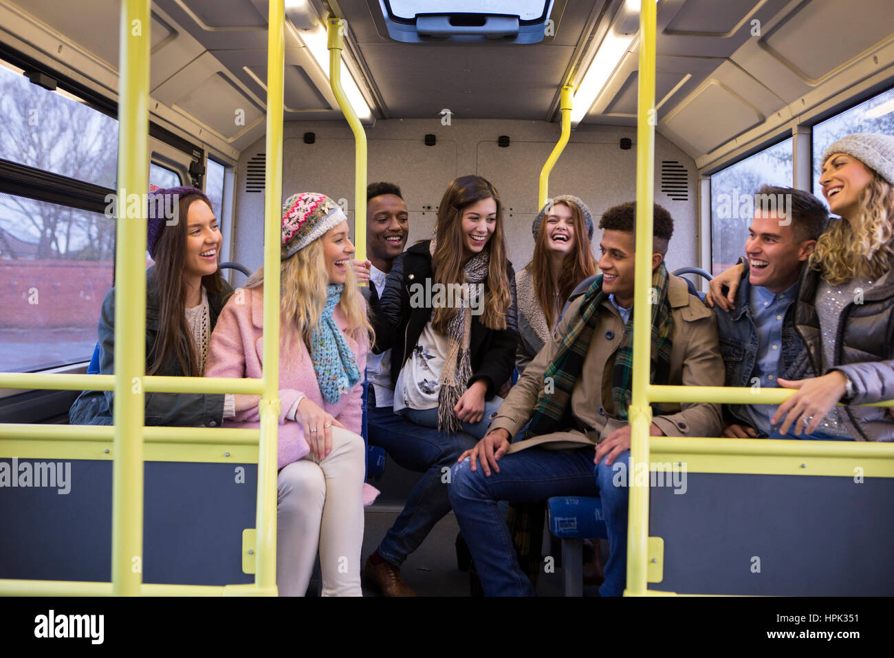 Group of young adults sitting together at the back of the bus. They are ...