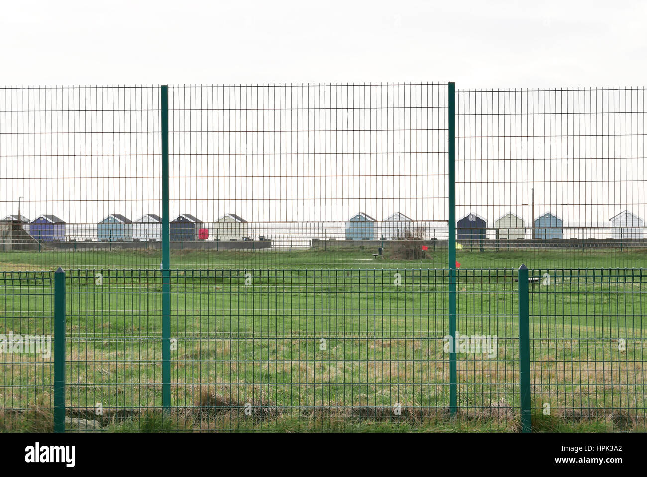 Row of beach huts viewed through security fence Stock Photo - Alamy
