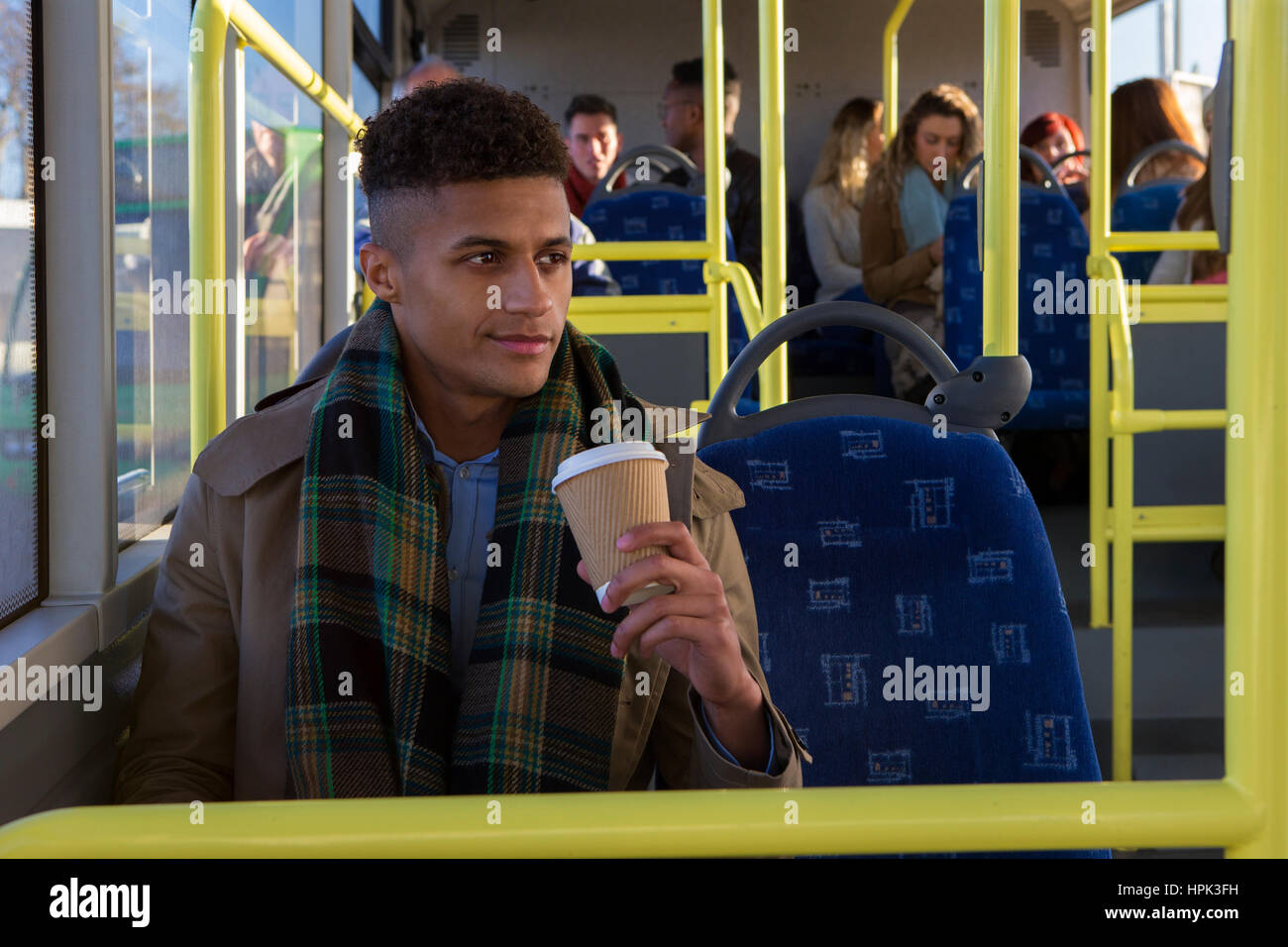 Attractive young man sitting on the bus with a cup of coffee. He is ...