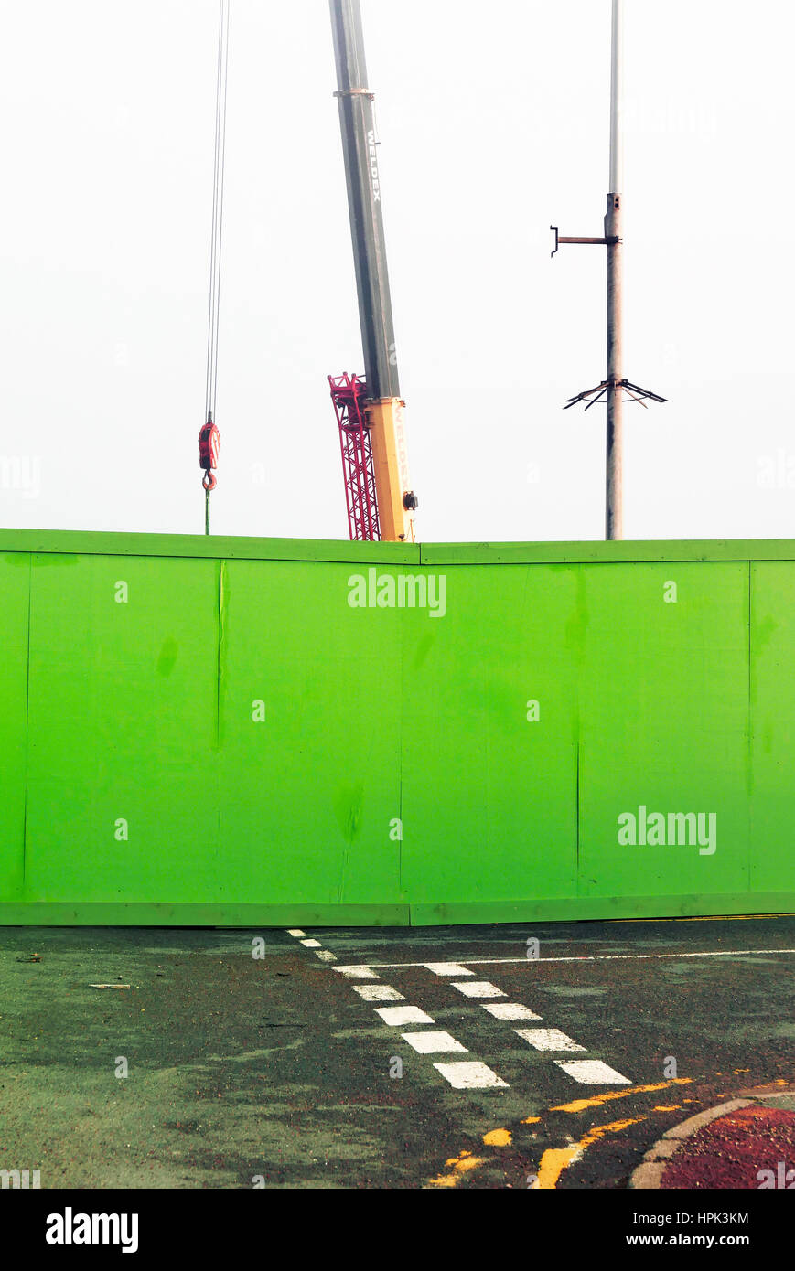 Crane and green fence Stock Photo - Alamy
