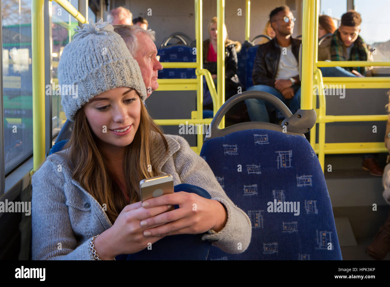 Young woman using her smartphone on the bus. There are other people ...