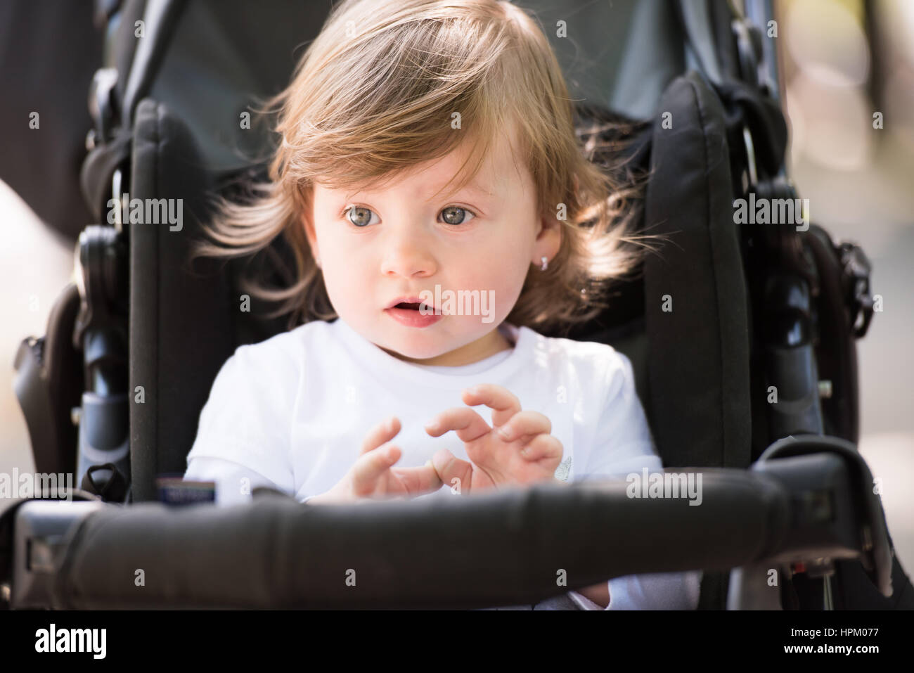 little and very beautiful baby girl sitting in the pram and waiting for ...