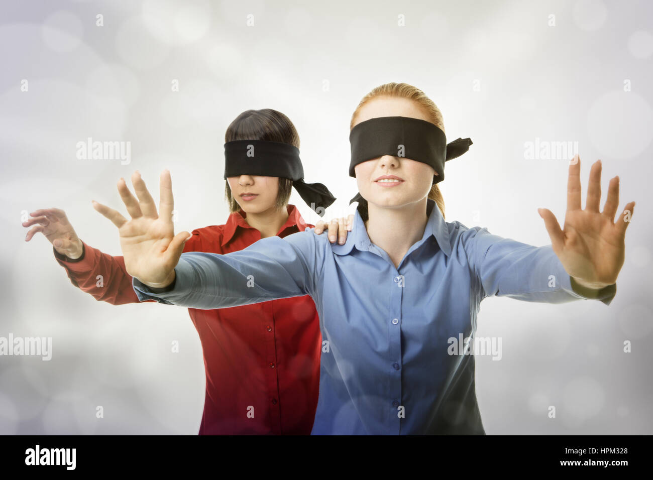 two business woman blind folded leading the other Stock Photo - Alamy