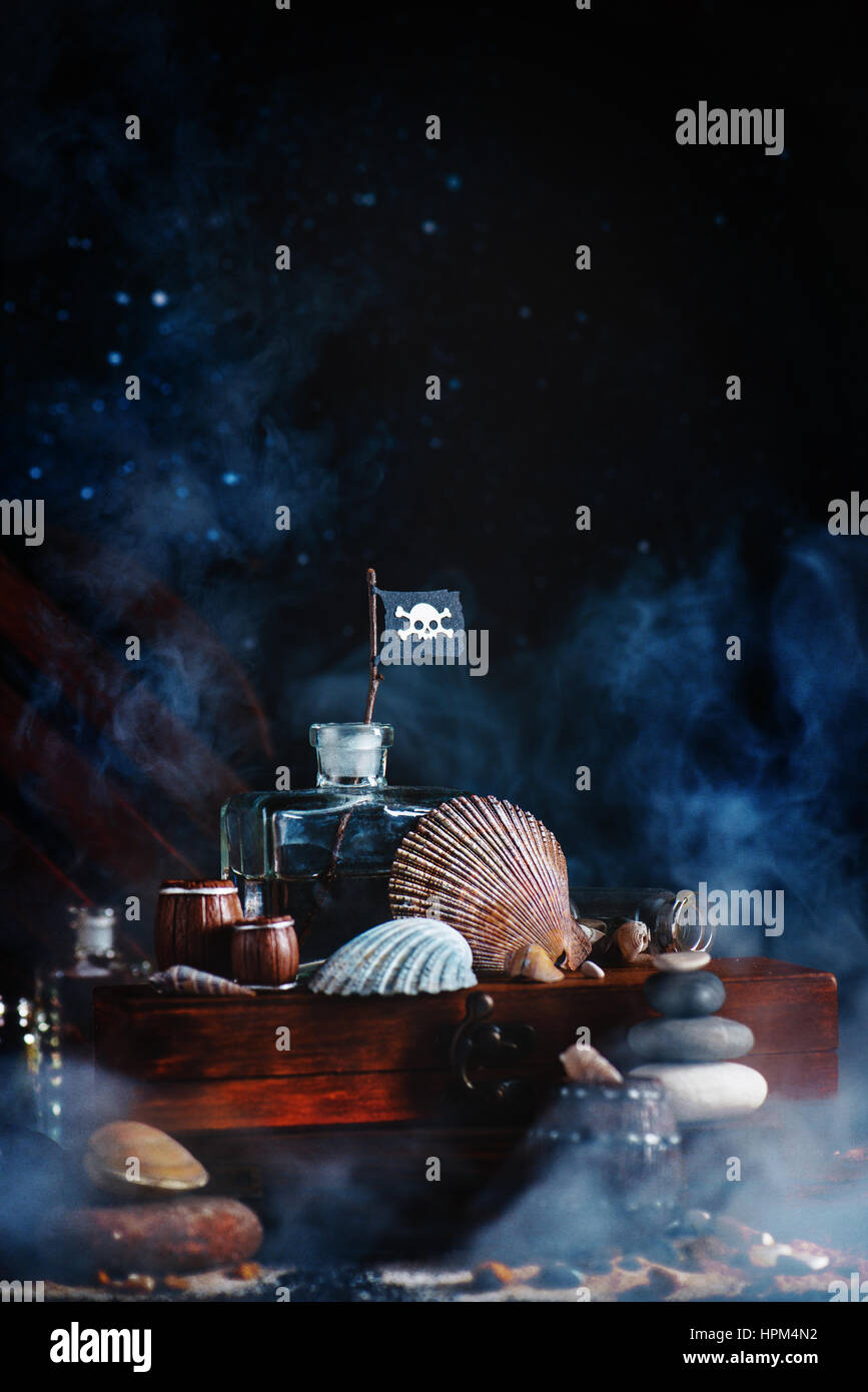 Marine still life with glass bottle, Jolly Roger, seashells, sand and ...