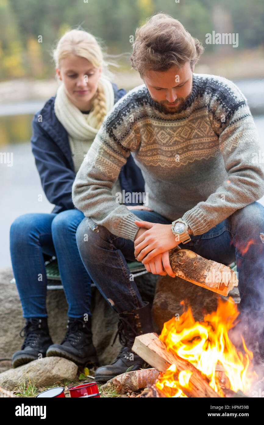 Young woman with man preparing bonfire during lakeside camping Stock ...