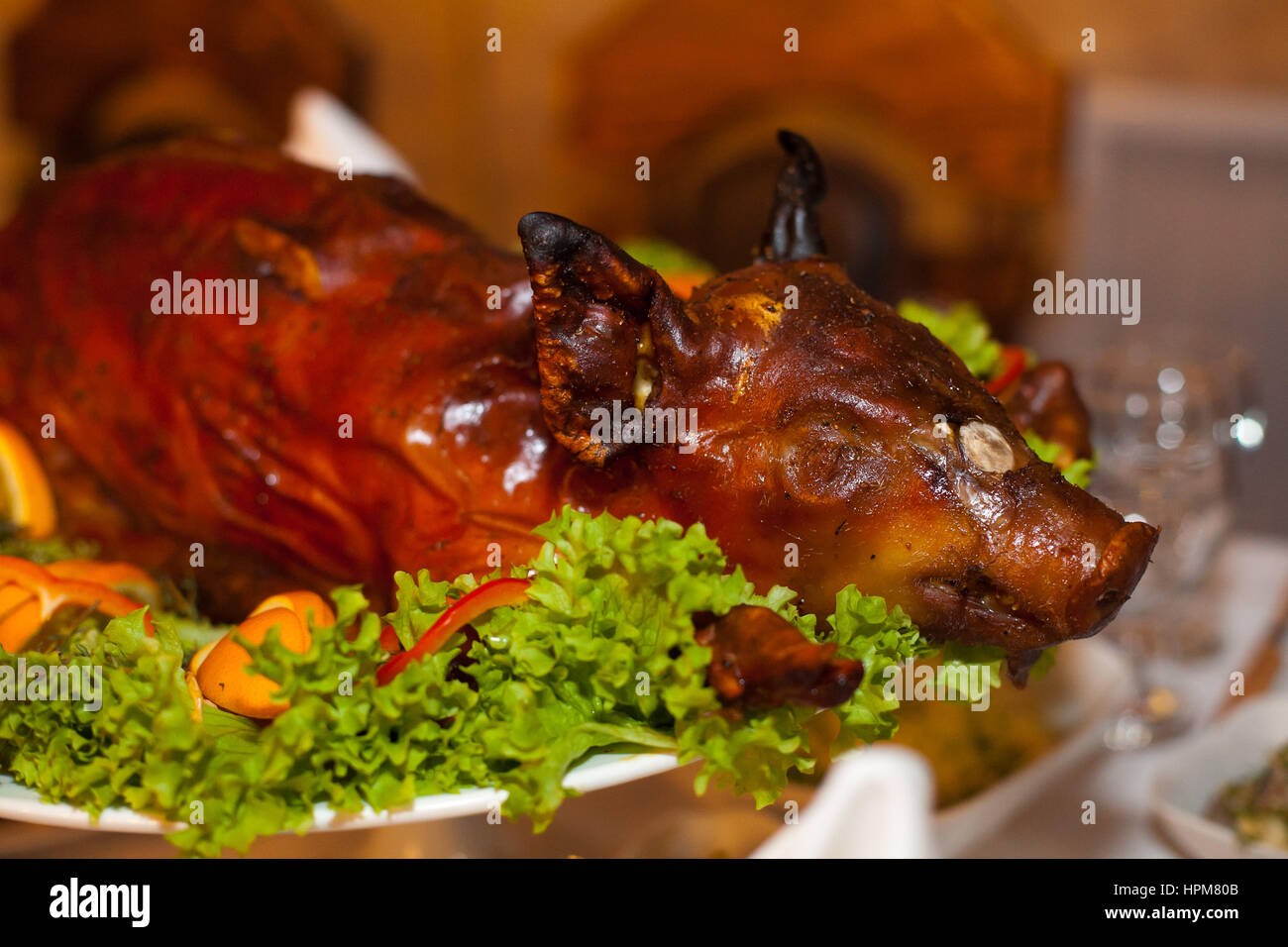 the young whole baked pig with a fragrant crisp lying on a festive dish ...