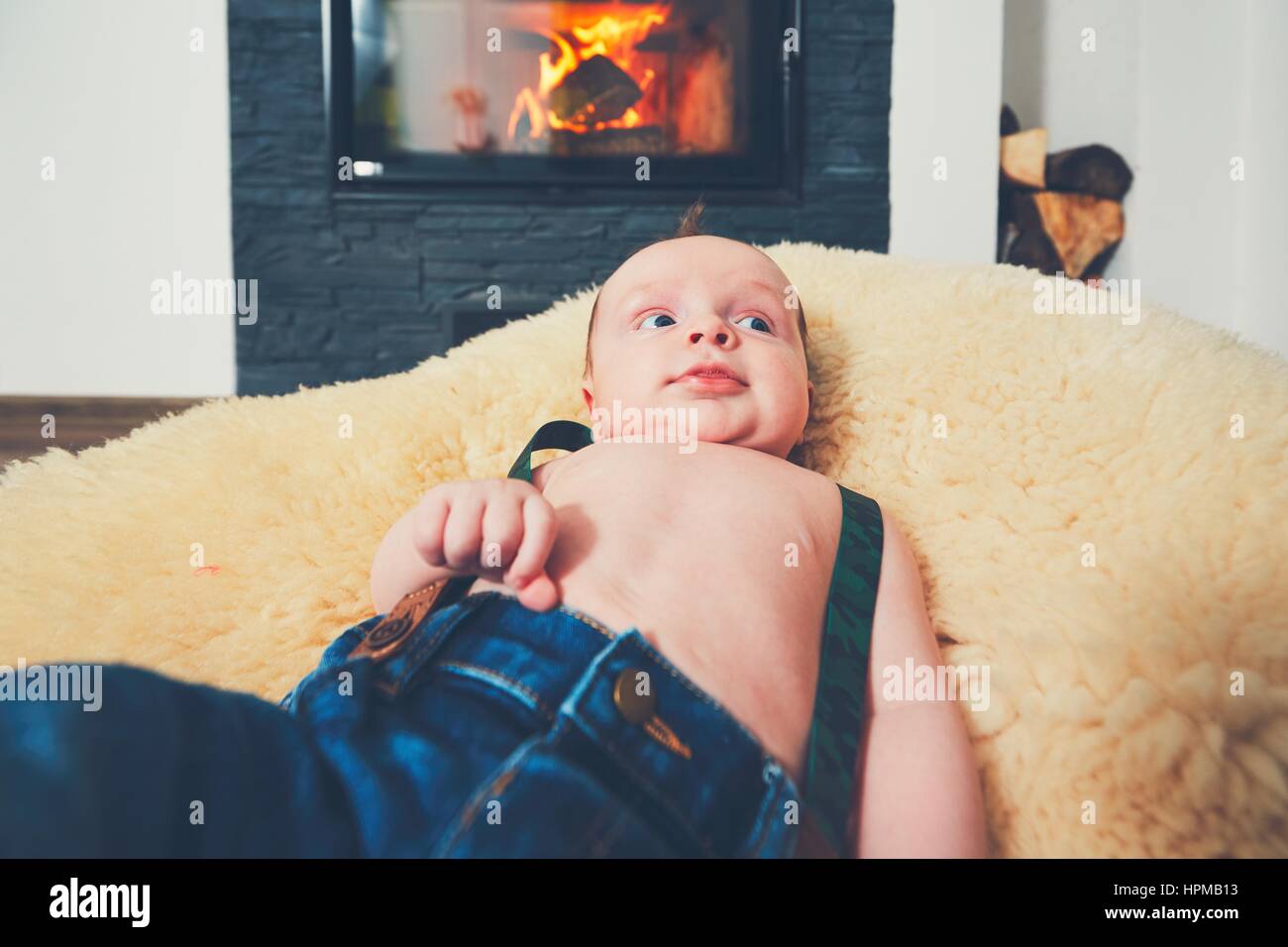 Little boy at home. Adorable baby resting on the blanket near fireplace ...