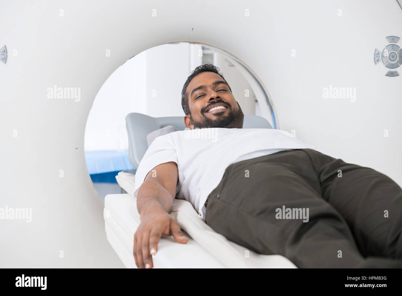Portrait of smiling mid adult male patient undergoing CT scan in ...