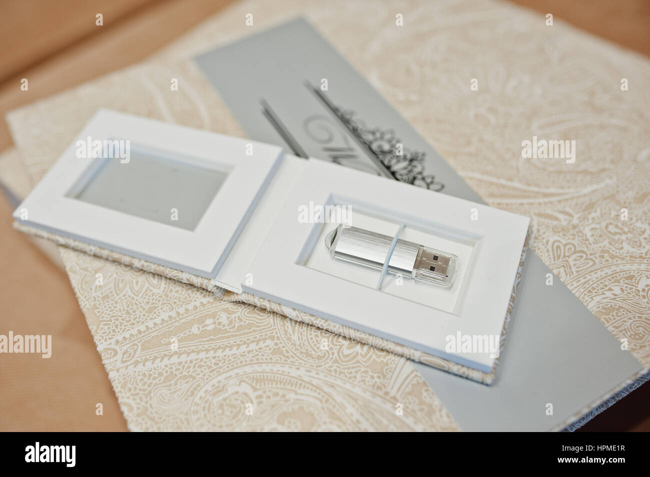 Silver flash drive on elegant wedding album and photo book from beige ...
