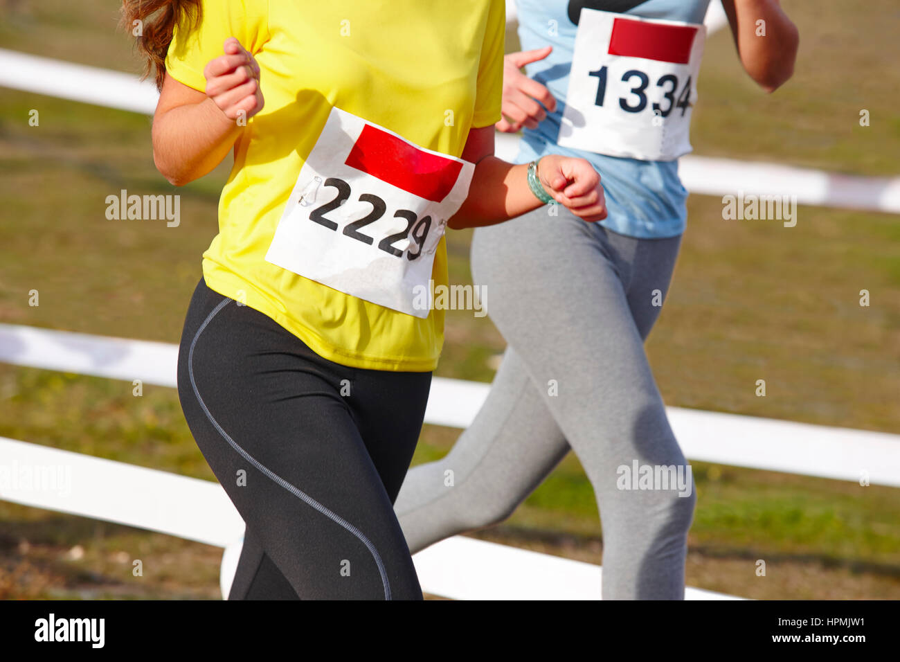 Young female athletic runners on a race. Outdoor circuit. Horizontal ...