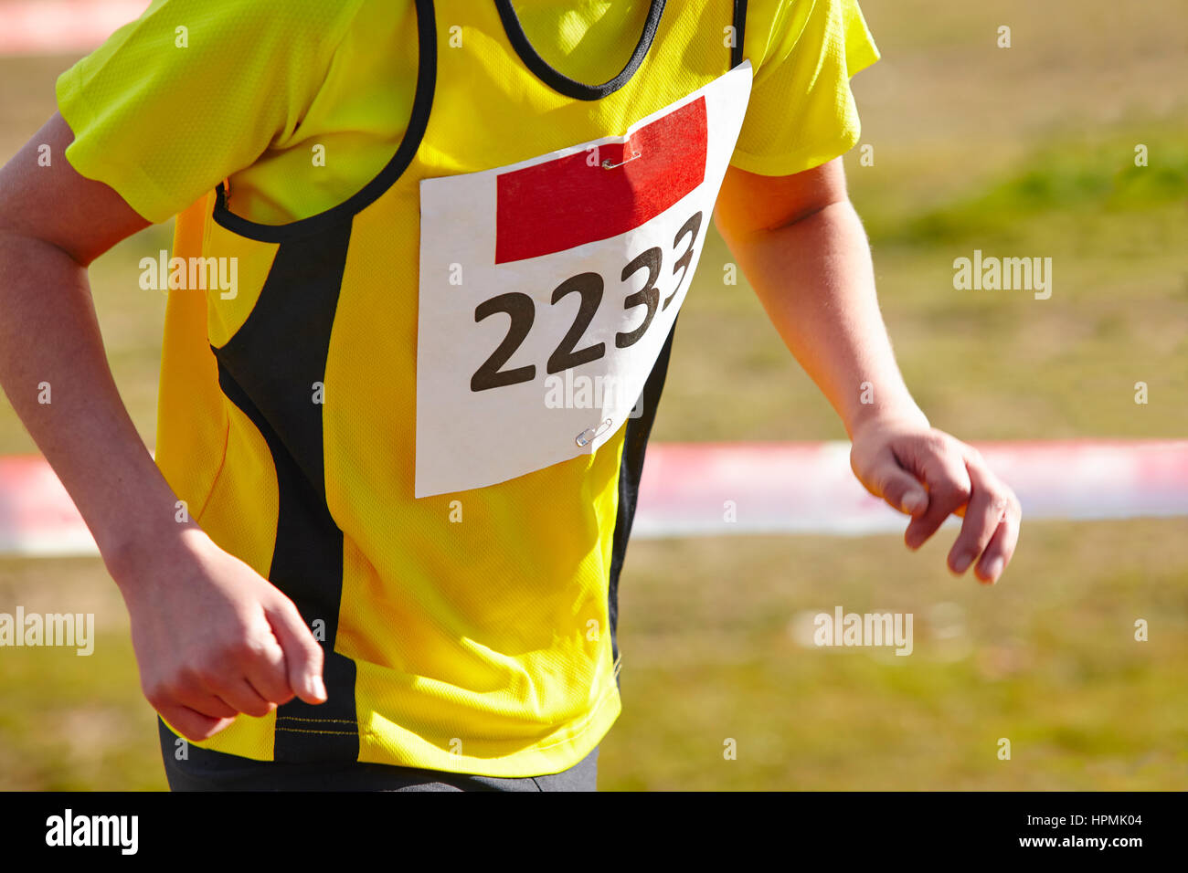 Young athletic runner with number on a race. Outdoor circuit ...