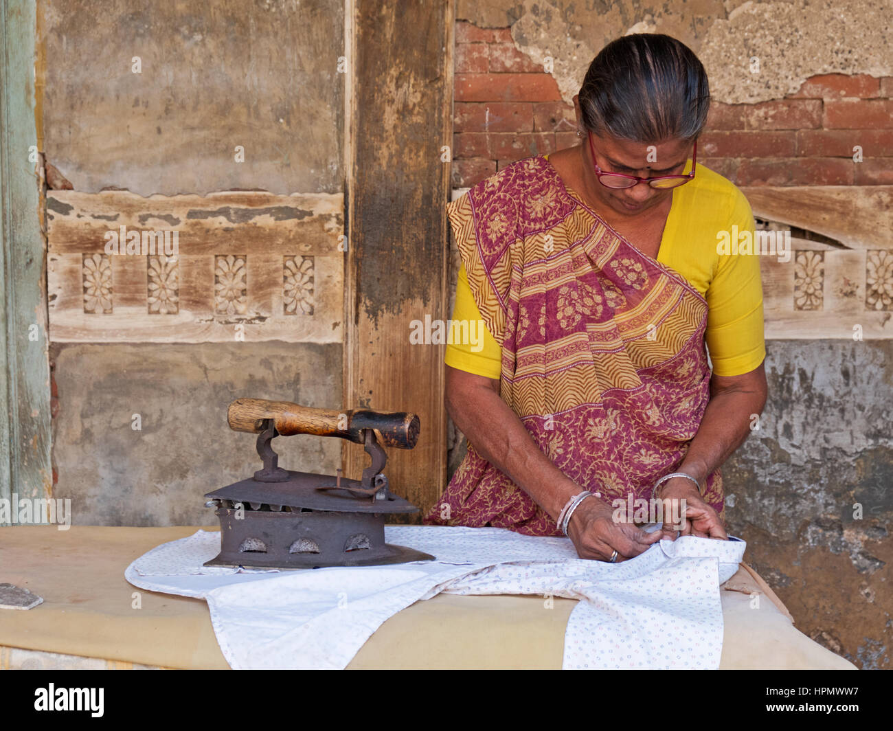 Unidentified woman in a back street in Ahmedabad, India, ironing ...