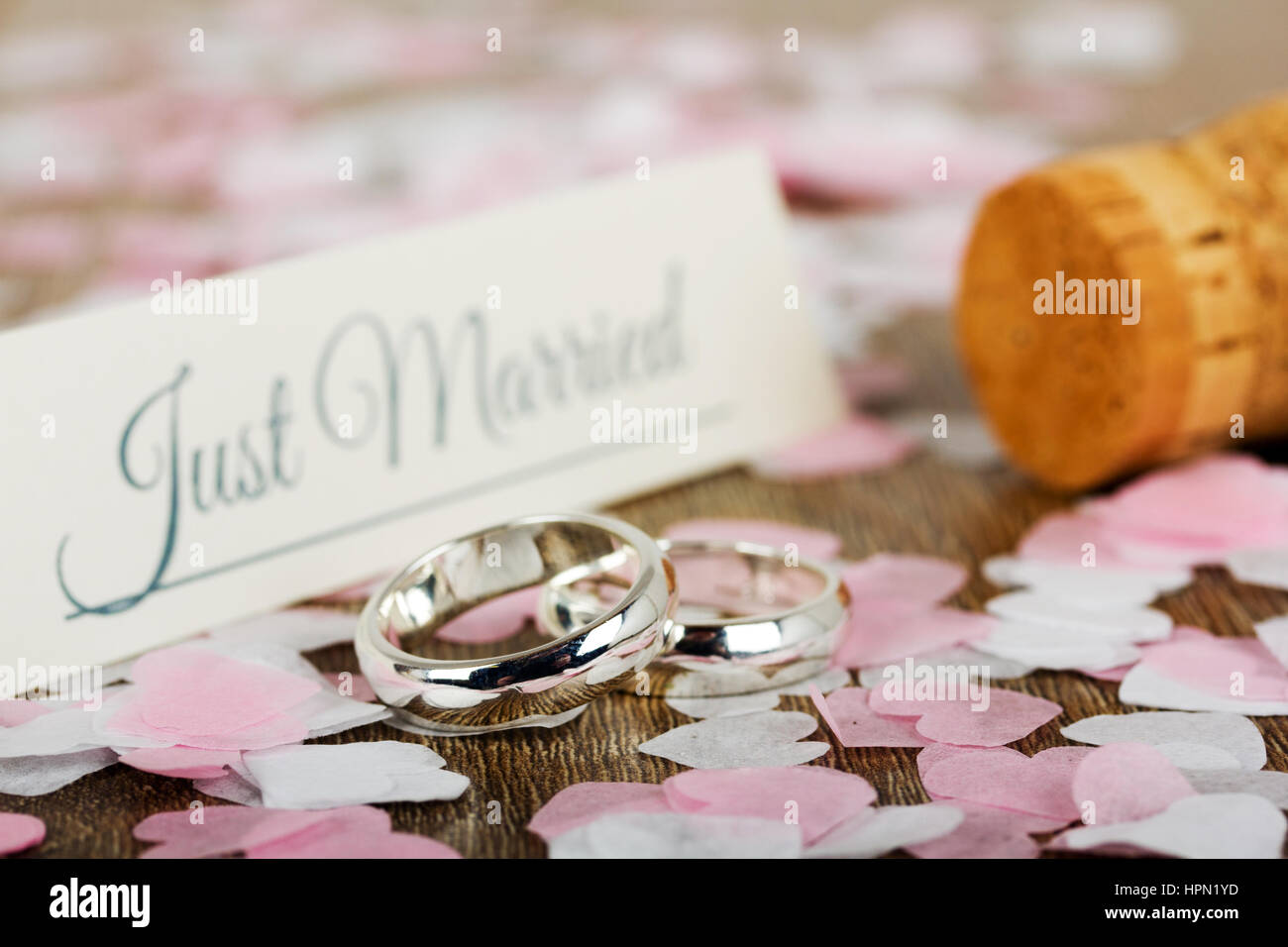 pair of white gold wedding rings on a wooden background with confetti ...
