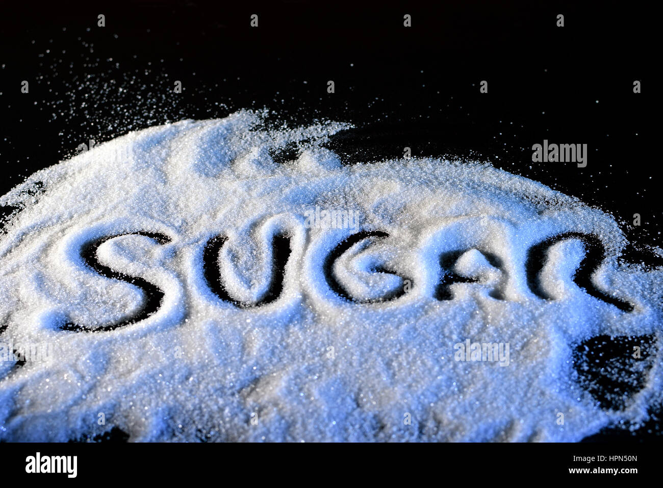 Word sugar written with finger to pile of white sugar Stock Photo - Alamy