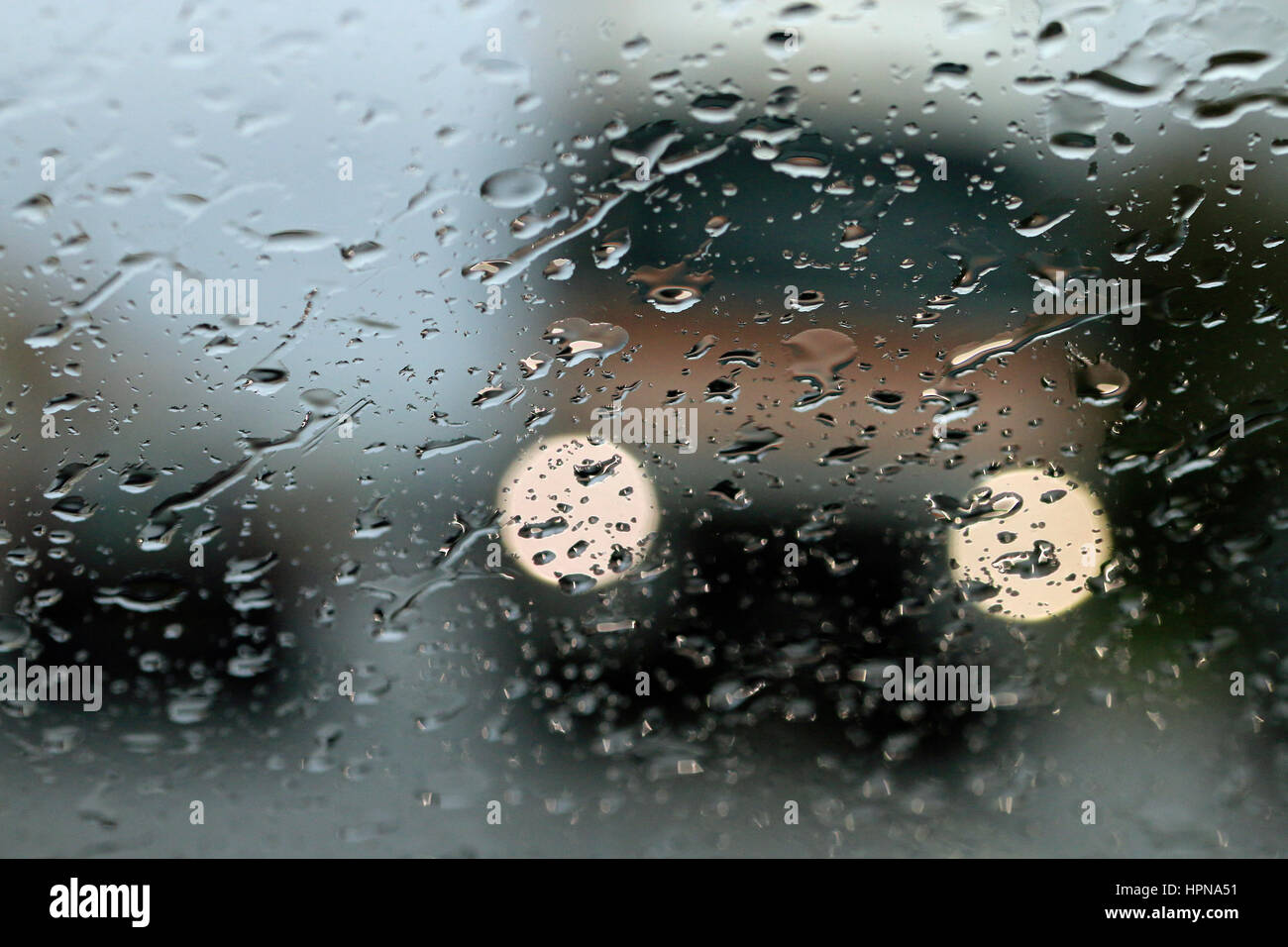 Headlights of oncoming traffic seen through rain on a windscreen Stock ...