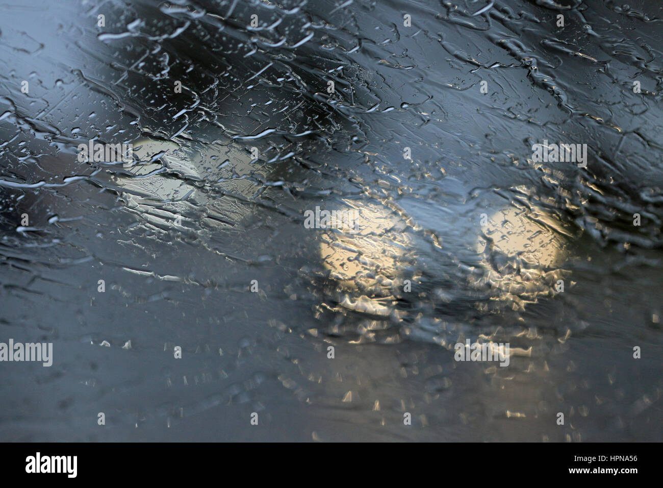 Headlights of oncoming traffic seen through rain on a windscreen Stock ...