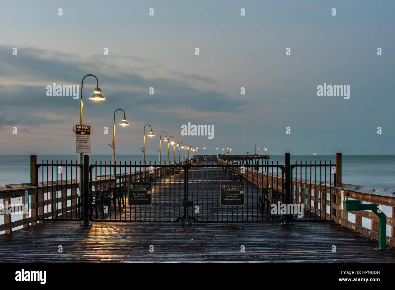 Panoramic view of lamps glow along Ventura Pier behind locked gates at ...