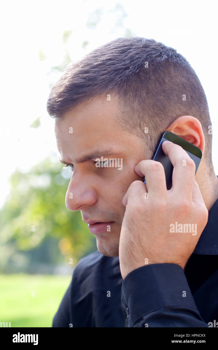 Handsome man talking on the phone in the park Stock Photo - Alamy