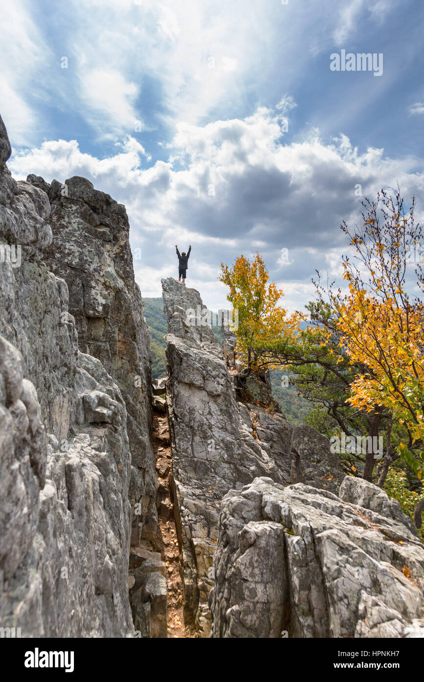 Young climber reaches the summit of the rocky granite mountain top of ...