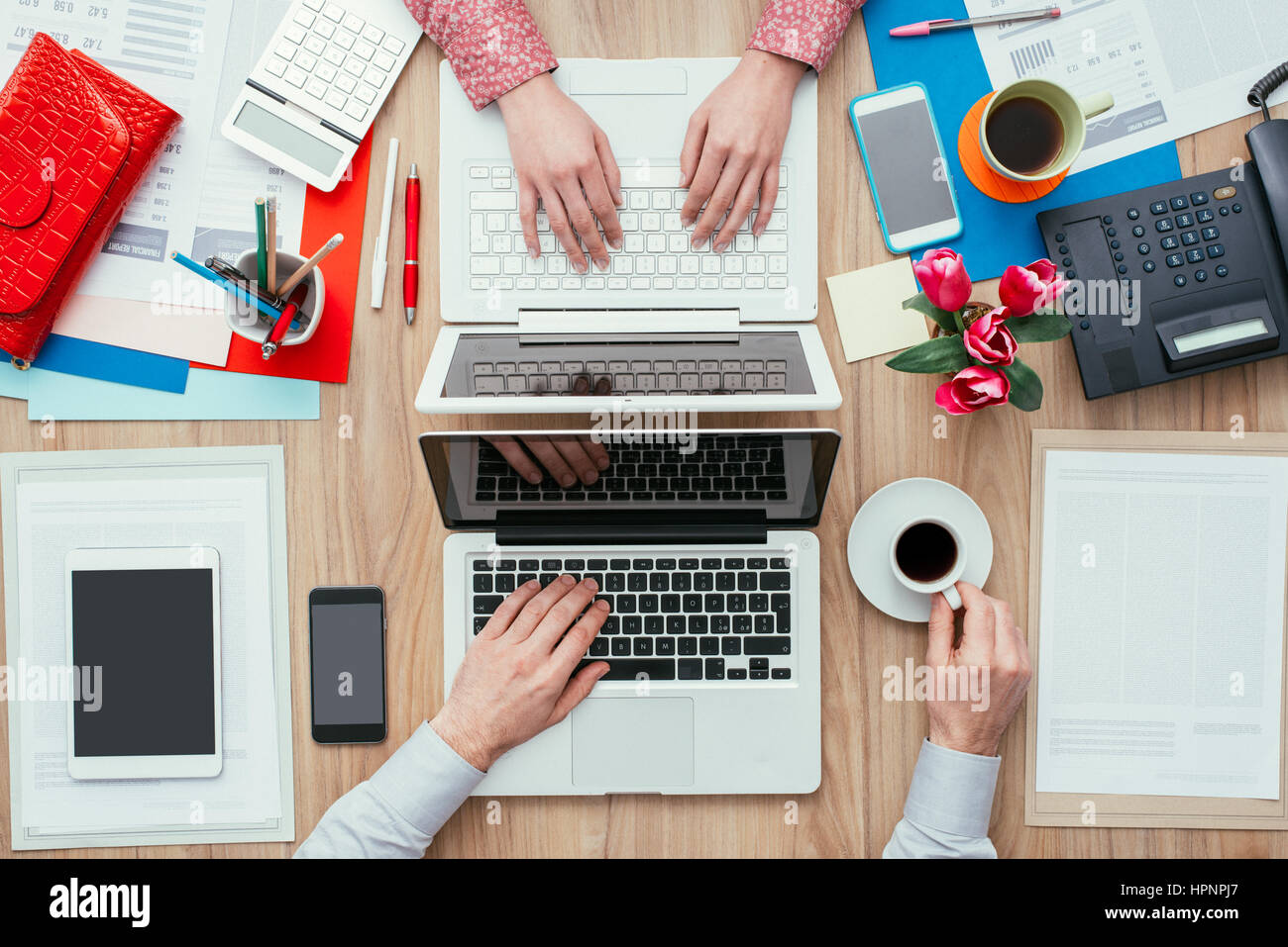 Coworkers sharing the same desk with customized workspace and working ...