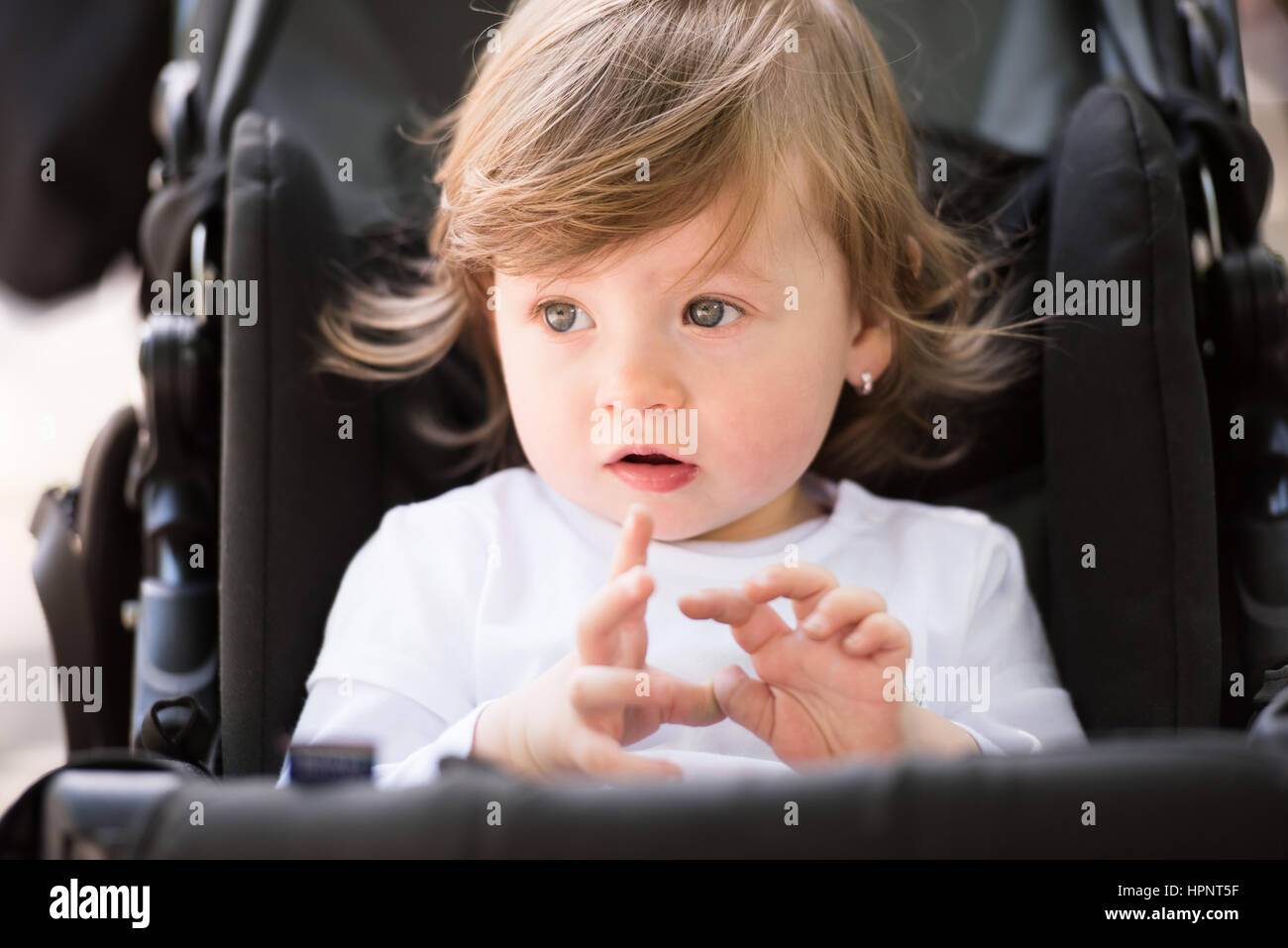 little and very beautiful baby girl sitting in the pram and waiting for ...