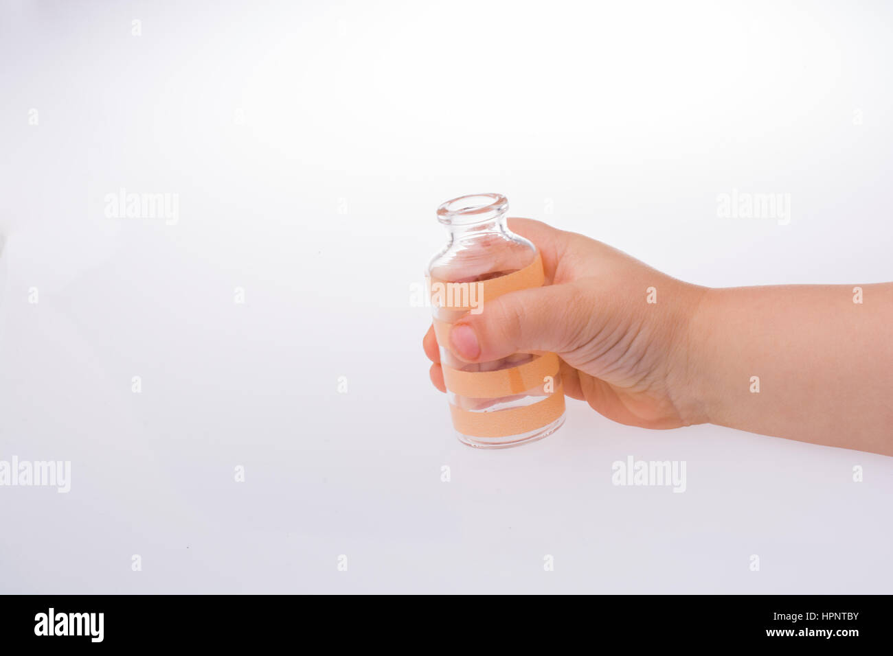 Little empty glass bottle in hand on a white background Stock Photo - Alamy