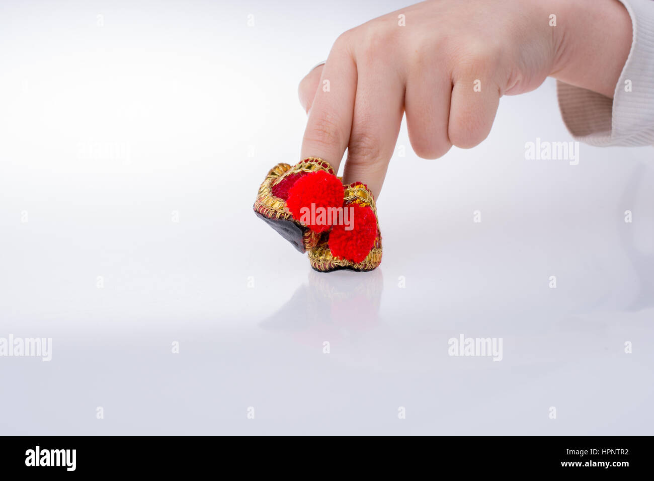 Hand holding traditional Turkish handmade shoes on white background ...