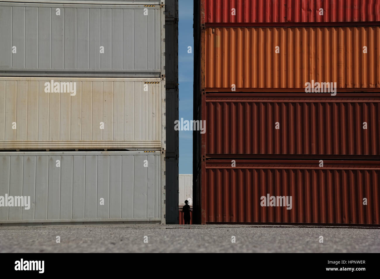 silhouette of person standing between stacks of cargo containers Stock ...