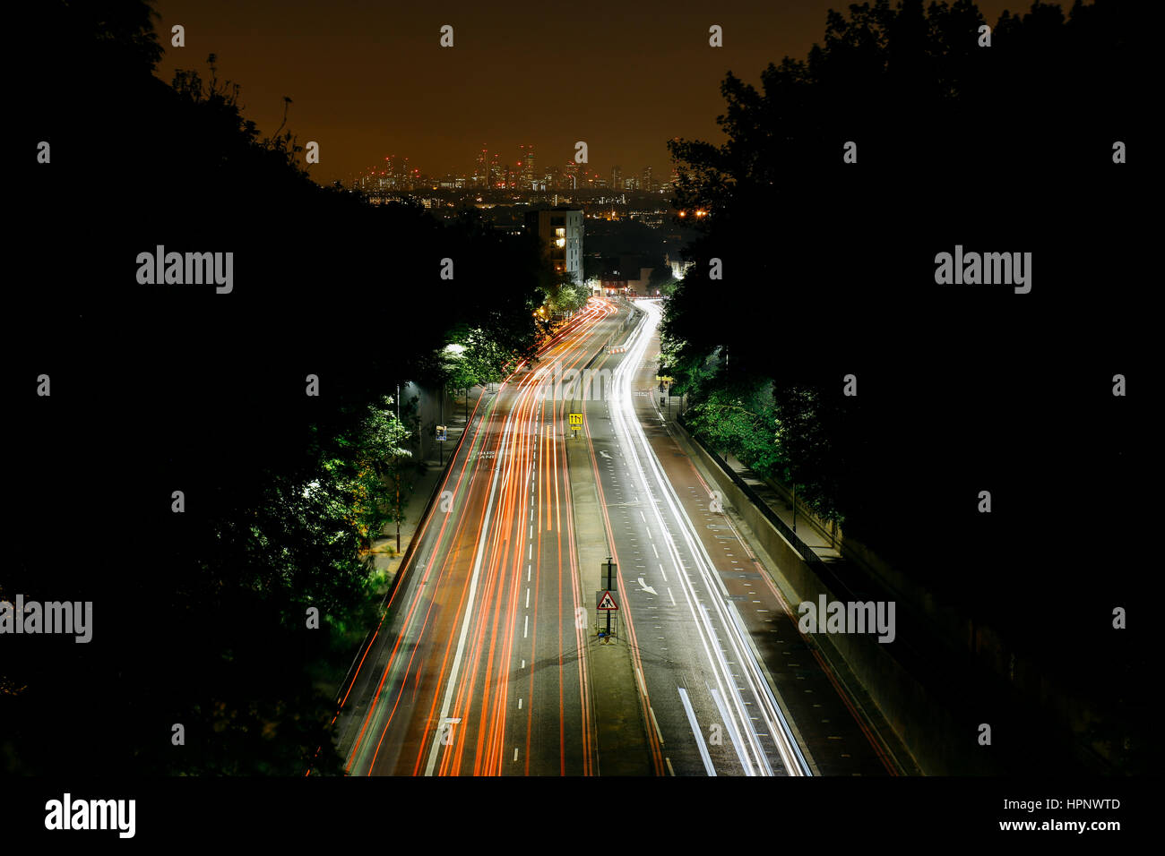 Aerial view of traffic light trails going into London, city skyline on ...
