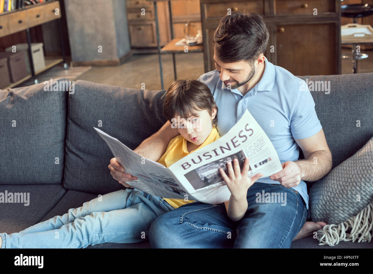 son reading newspaper to father at home Stock Photo - Alamy