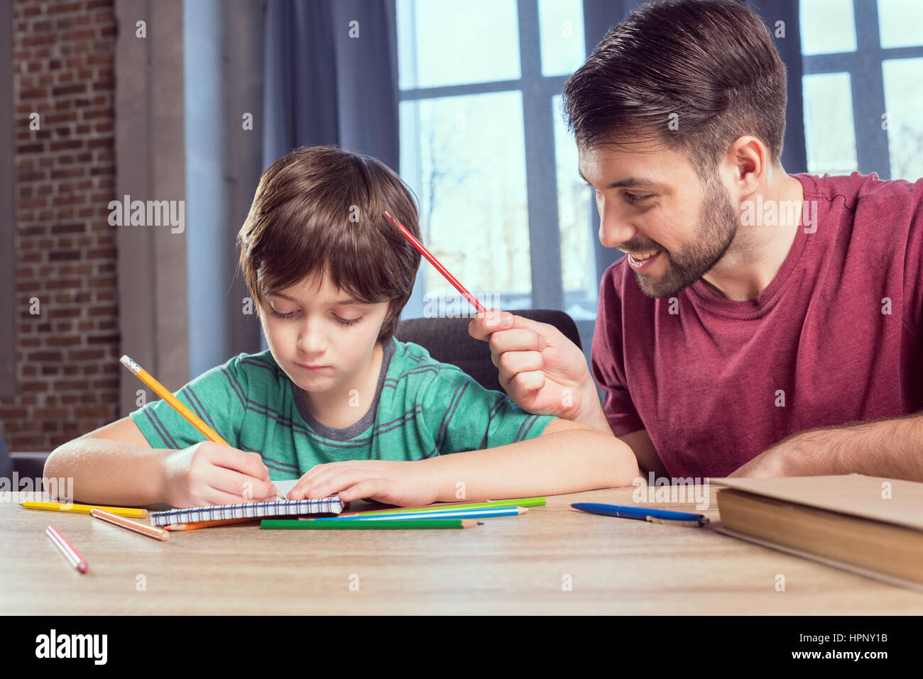 father helping concentrated son doing homework Stock Photo - Alamy