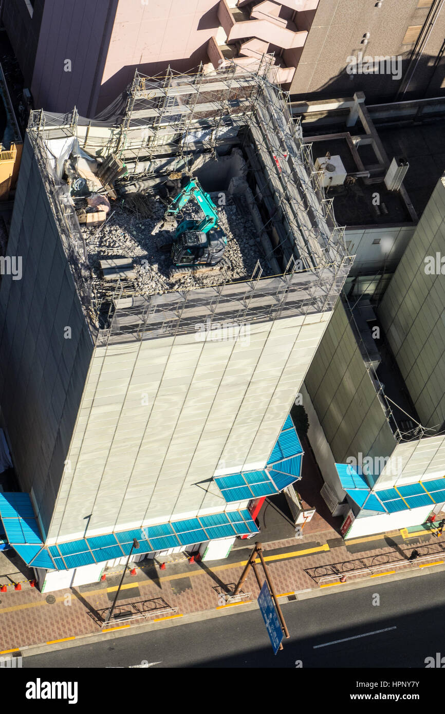 A mechanical shovel atop a tall building clearing rubble Stock Photo ...