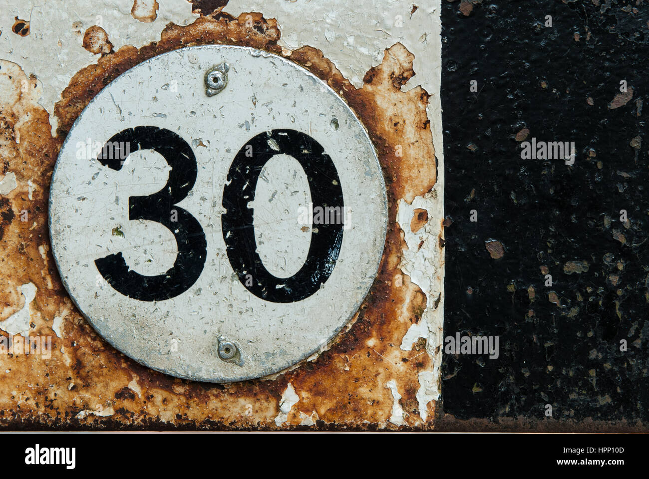 The number 30 on a metals disc with rusty background Stock Photo - Alamy