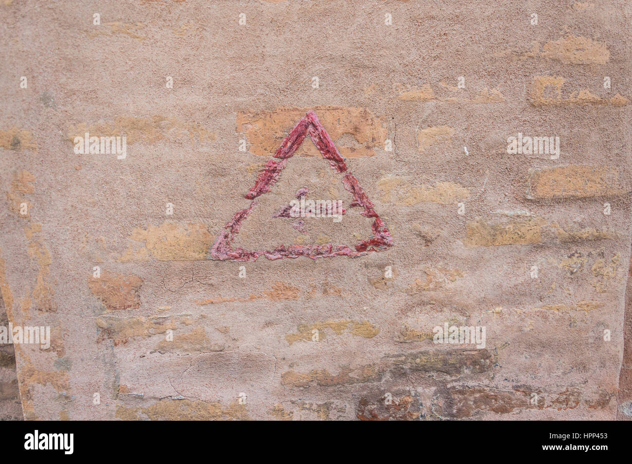 wall background with an old painted red arrow inside a triangular shape ...
