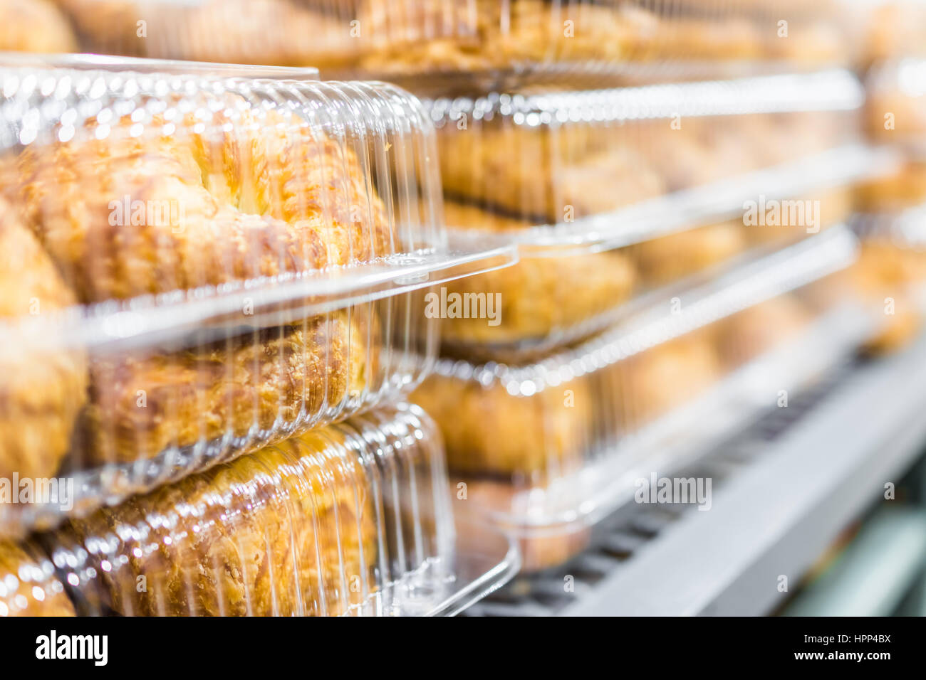 Many plain croissants packaged in plastic boxes on display in store ...
