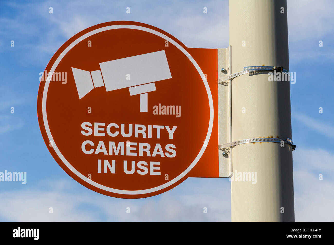 Orange Security Camera In Use Sign on Gray Post and Partly Sunny ...