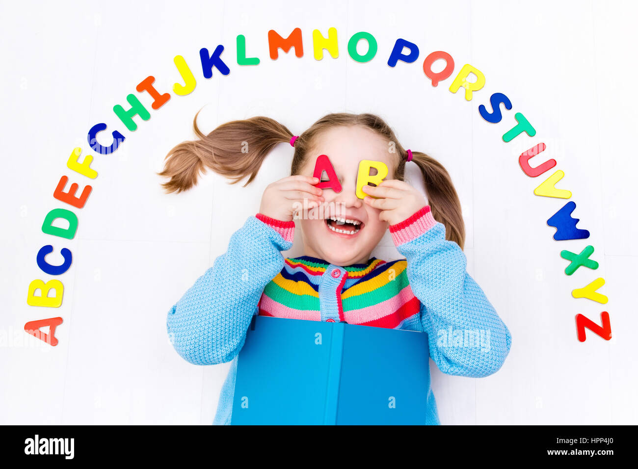 Happy preschool child learning to read and write playing with colorful ...